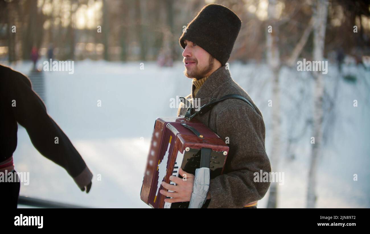 Russian traditions - a man with a beard is actively playing the button ...