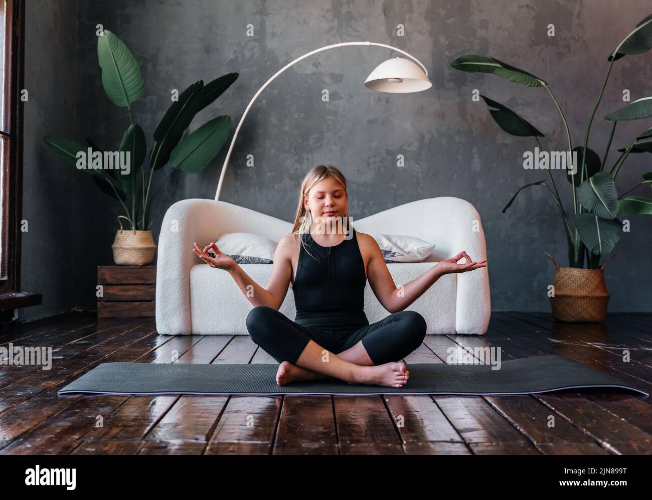 Young attractive girl practicing yoga, sitting in Half Lotus exercise ...