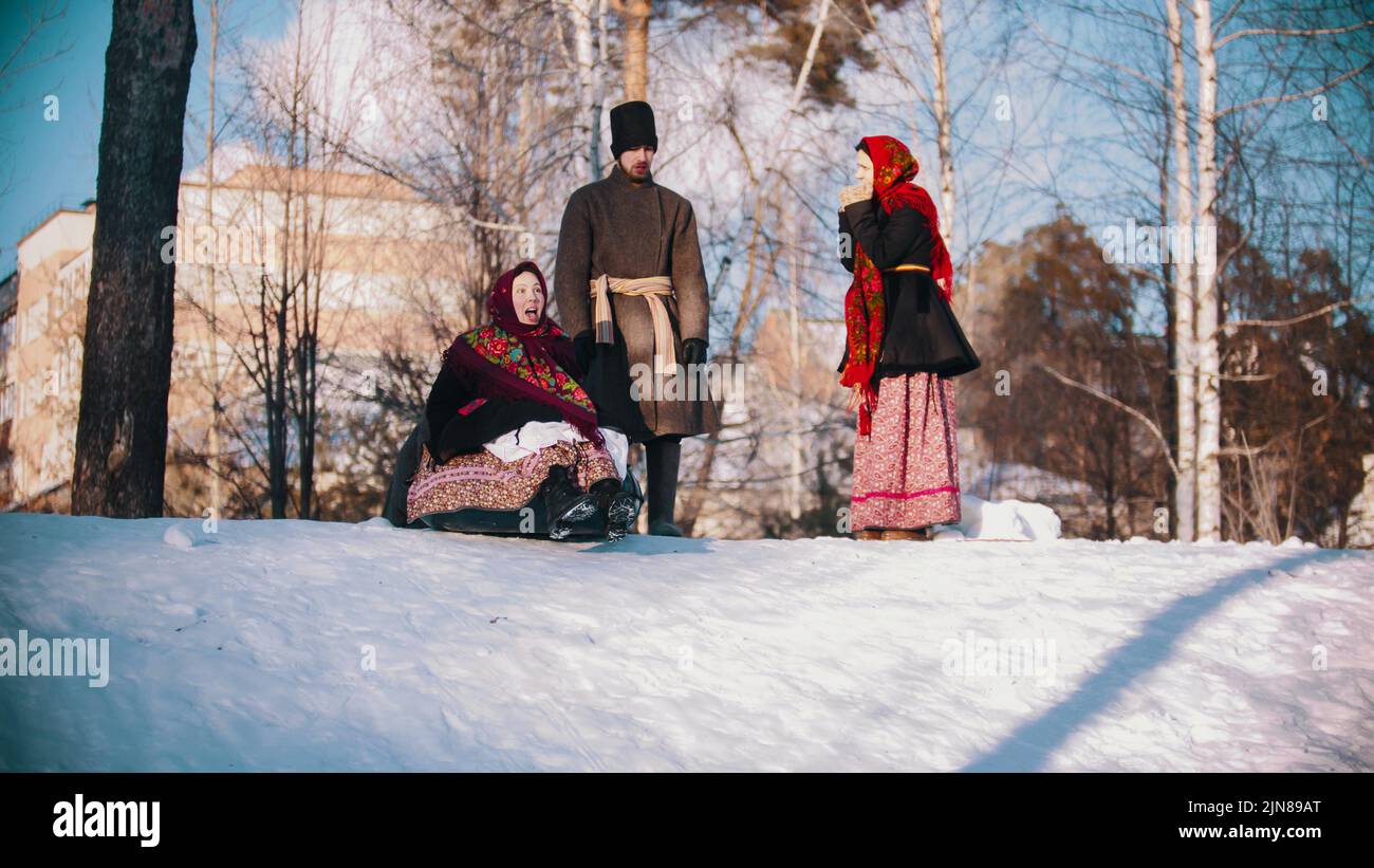 Russian folk - men and women in Russian folk costumes are riding a snow ...