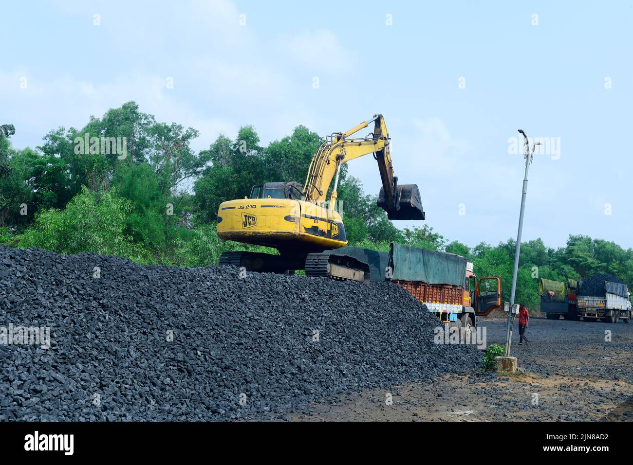 Earth excavator stationed on a heap of charcoal loading coal into a ...