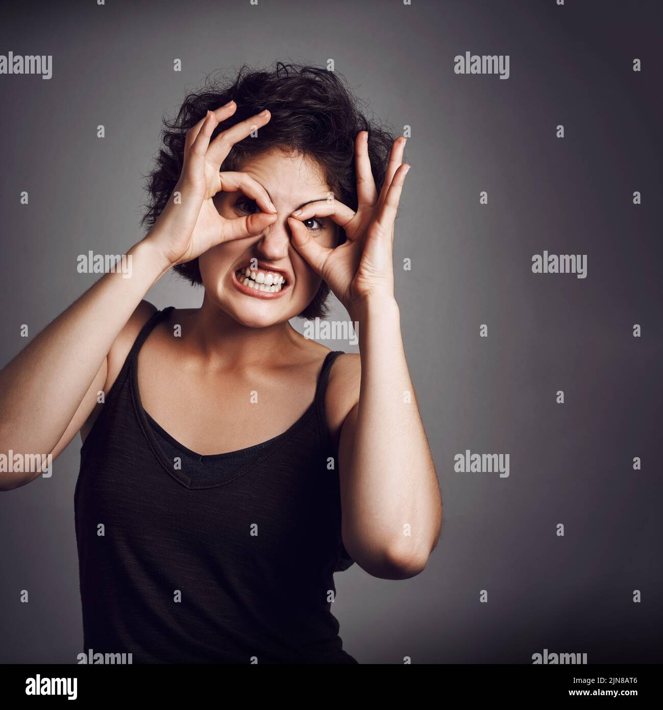 I will catch you through these. Studio portrait of an attractive young woman making a funny face ...