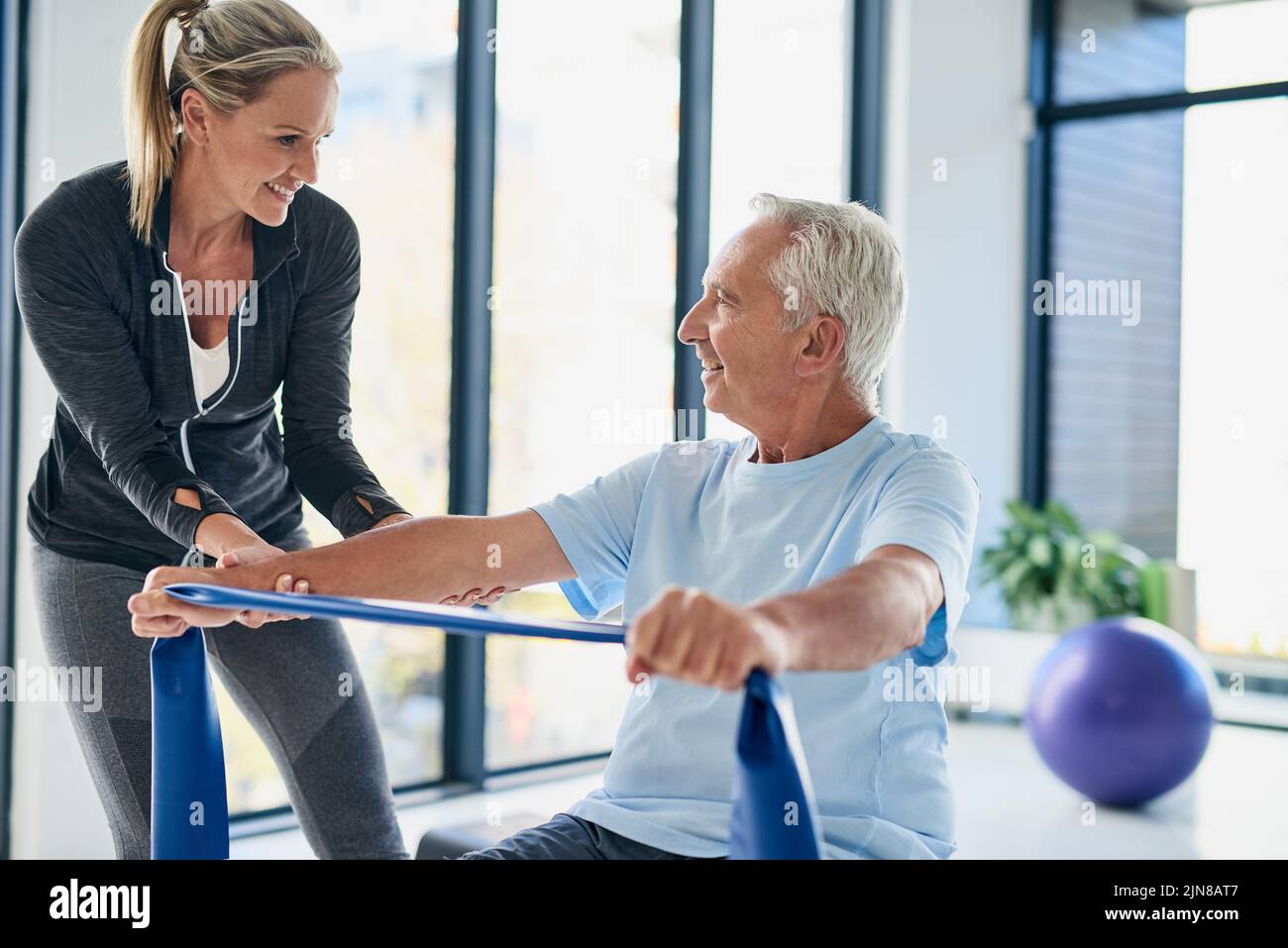 Youre doing a good job. a female physiotherapist helping a senior man ...