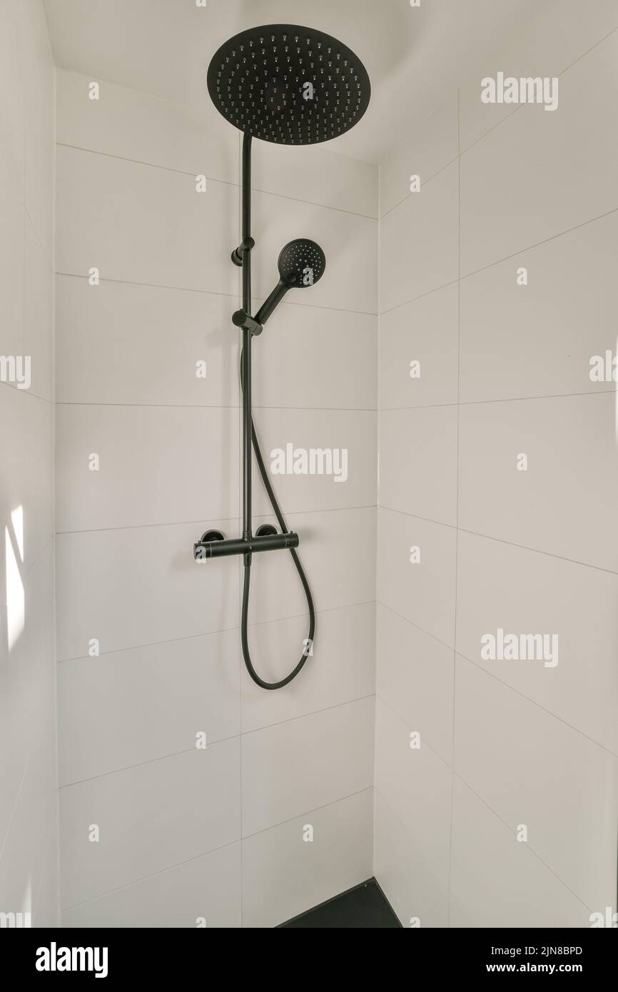 Shower faucets attached to tiled wall near glass partition and ...