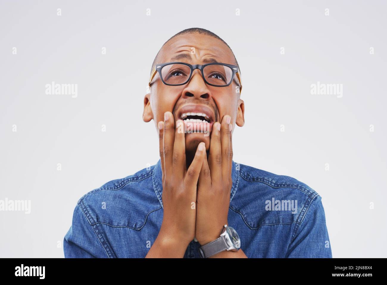 Why me. Studio shot of a young man crying while standing against a gray ...
