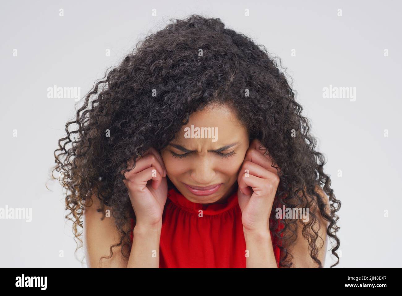 I cant hear you. Studio shot of a young woman crying while standing ...