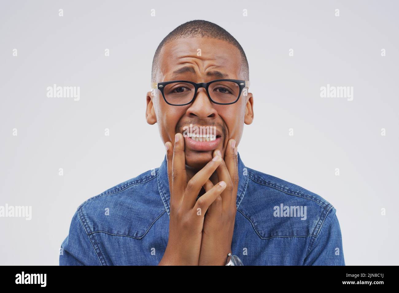 Why me. Studio shot of a young man crying while standing against a gray ...