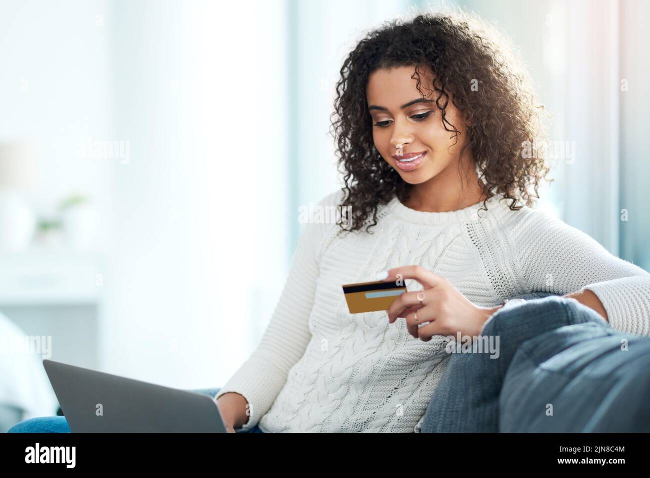 Shop the smart way. a young woman holding her credit card while using ...