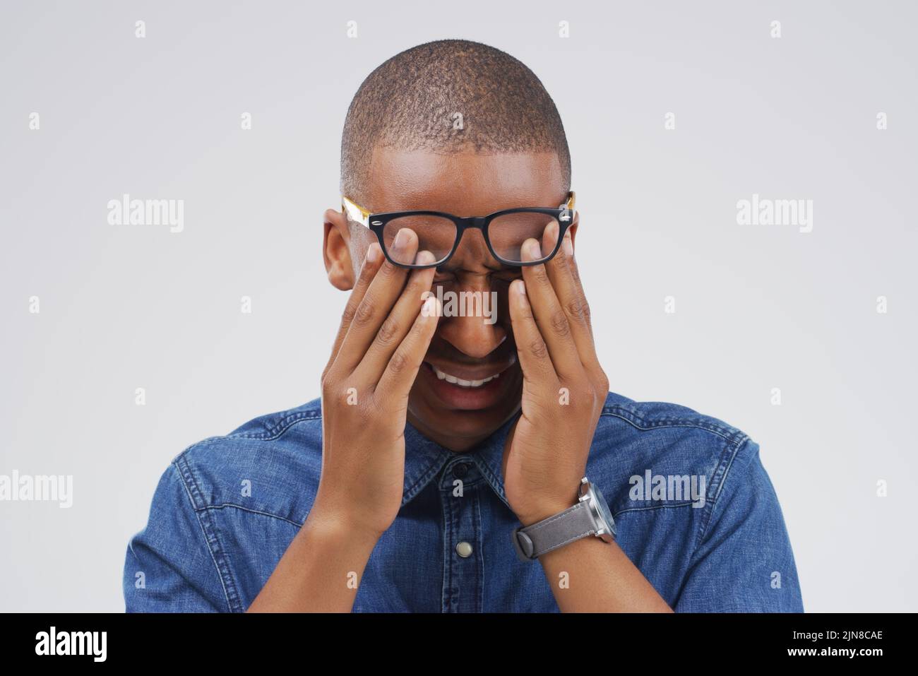 Why me. Studio shot of a young man crying while standing against a gray ...