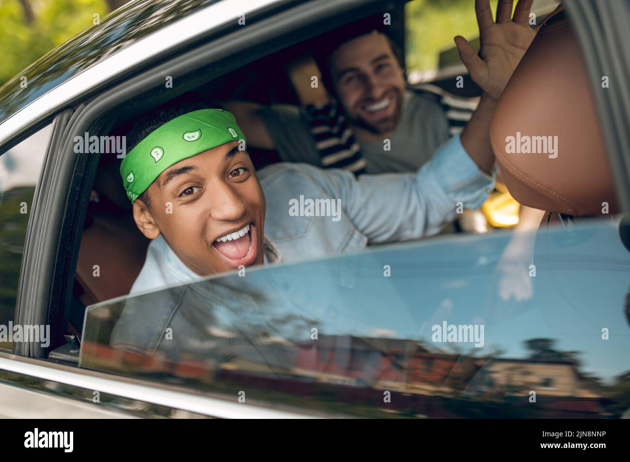 Group of friends driving in a car and looking excited Stock Photo - Alamy