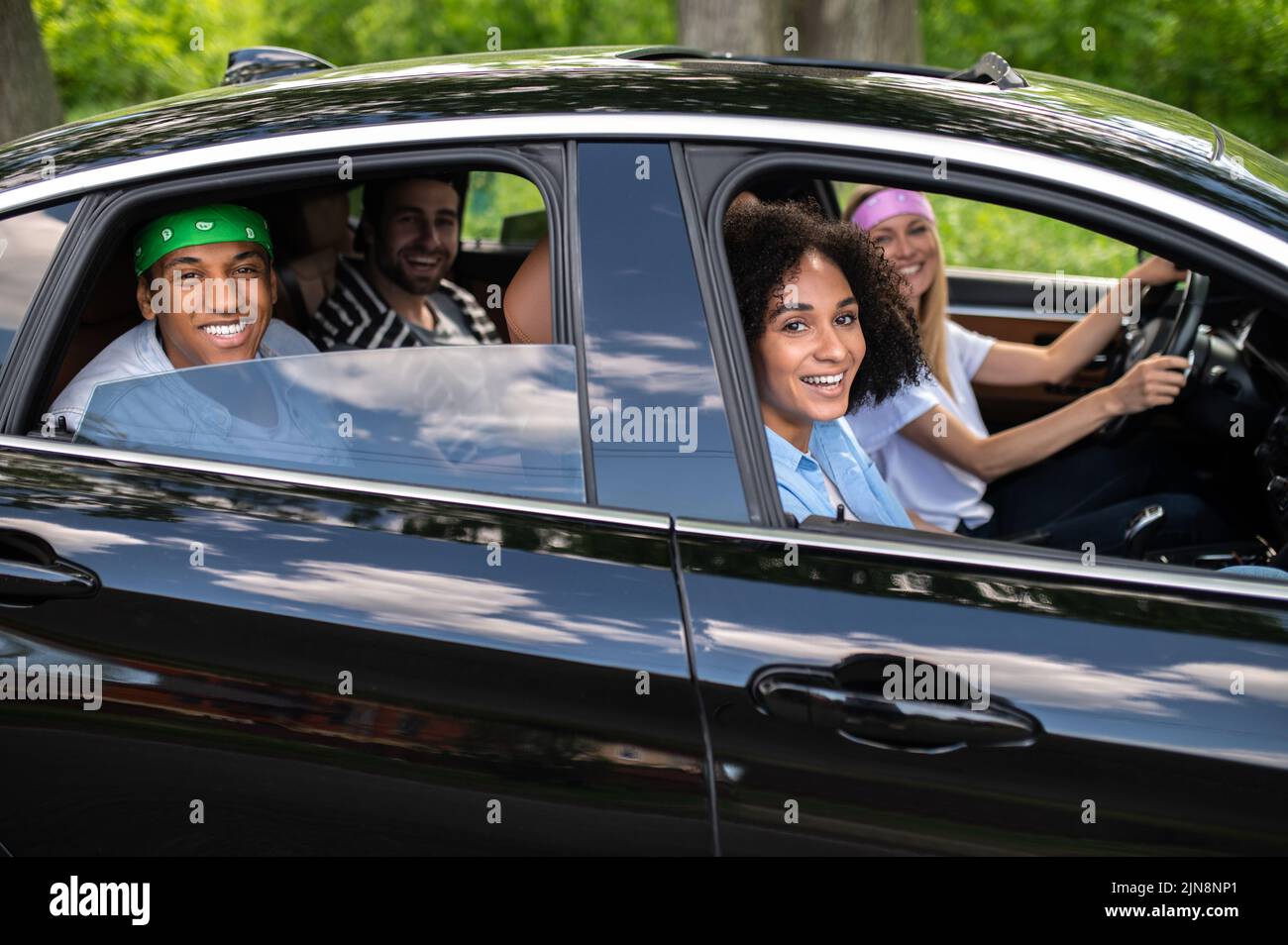 Group of friends driving in a car and looking excited Stock Photo - Alamy