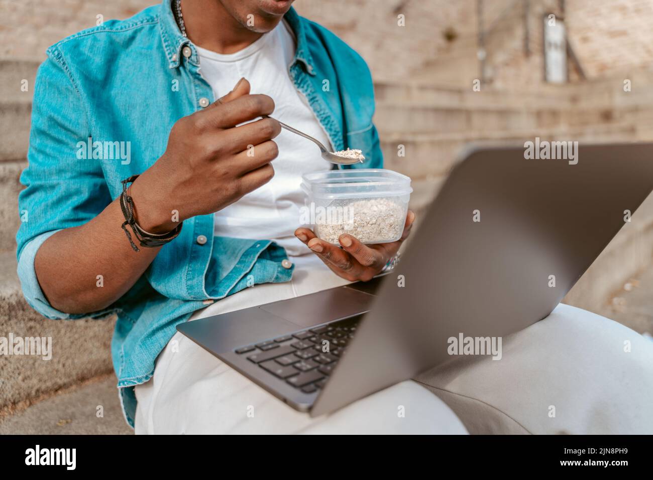 Guy eating in front of laptop outdoors Stock Photo - Alamy