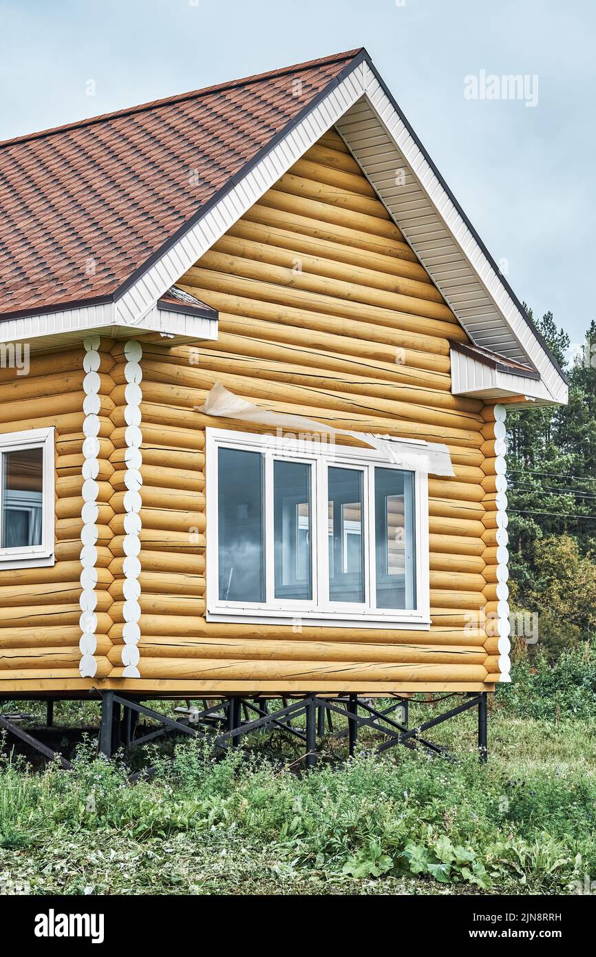 Log house on piled metal foundation built in countryside. Small ...