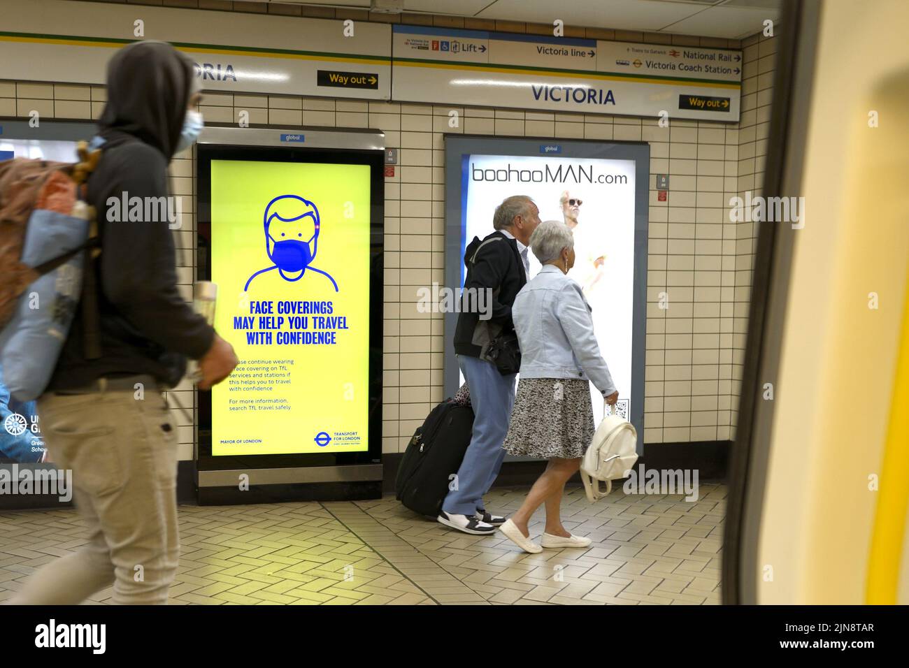 London, England, UK. Man with a face mask walking past a poster on face ...