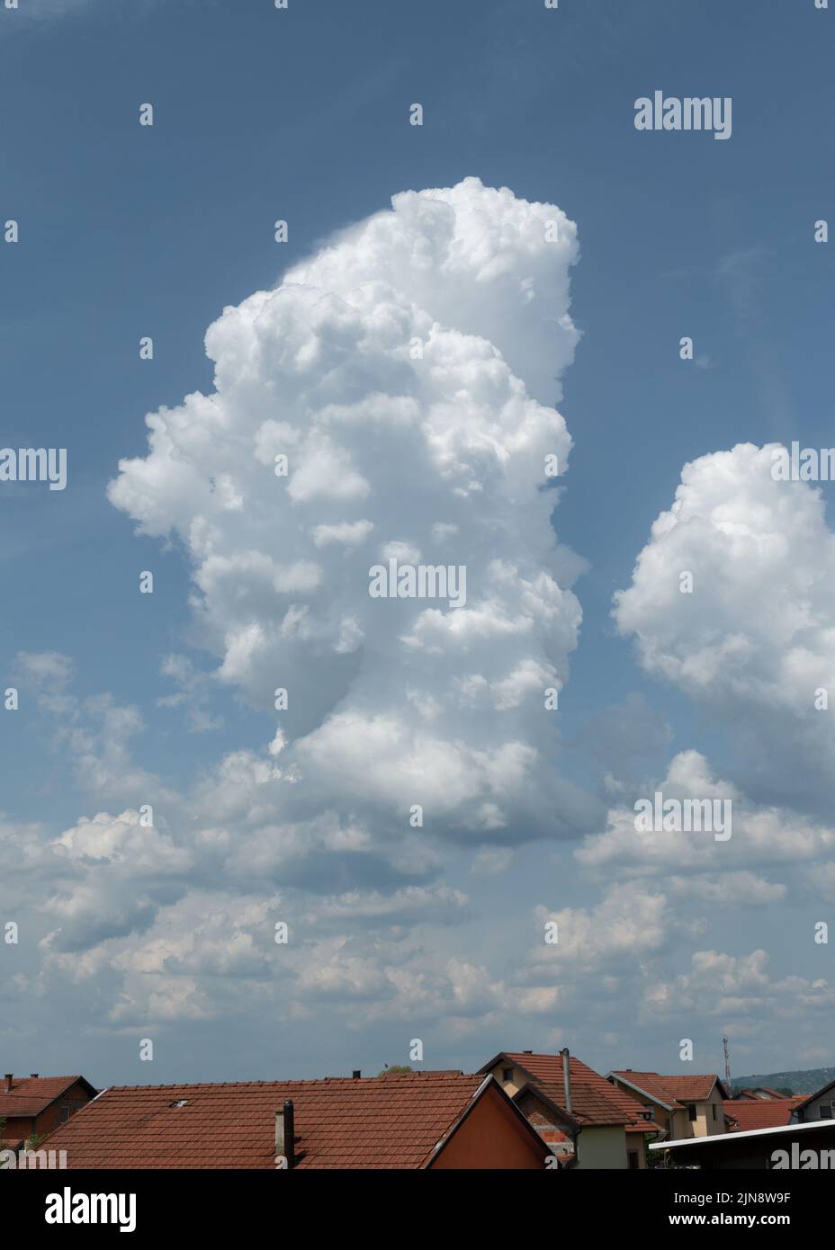 Cumulonimbus cloud above house roofs, vertical growing cloud Stock Photo - Alamy