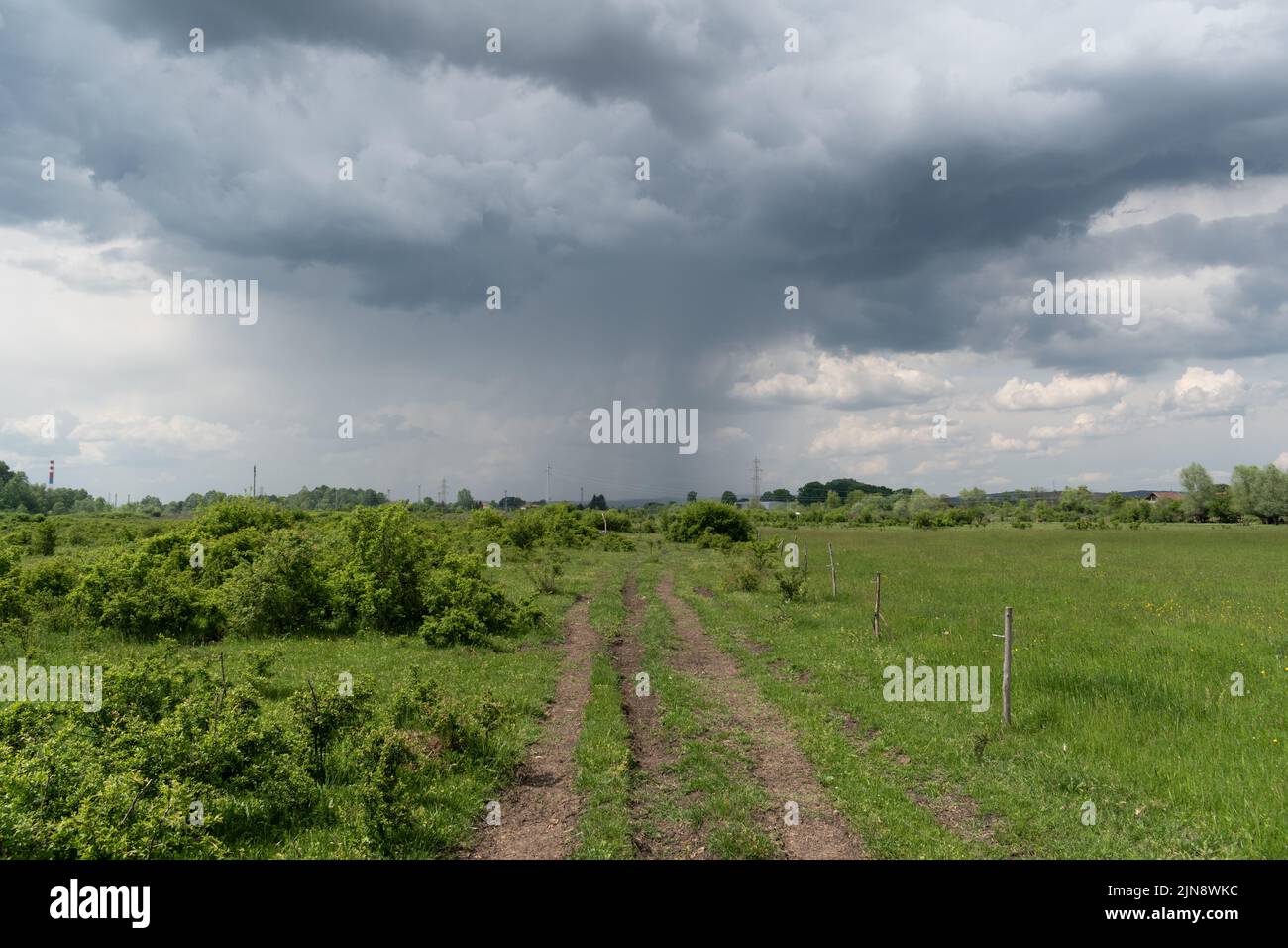 Dramatic storm cloud with rain over field with dirt road, stormy ...