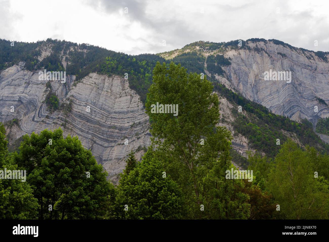 Distorted sedimentary rocks in the cliff face overlooking the town of ...