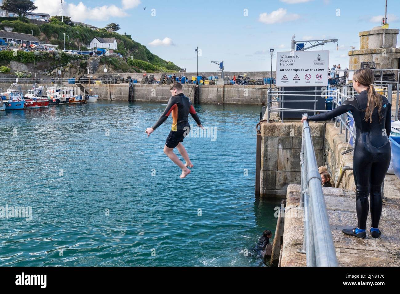 A young teenager jumping tombstoning into the sea at high tide from the ...