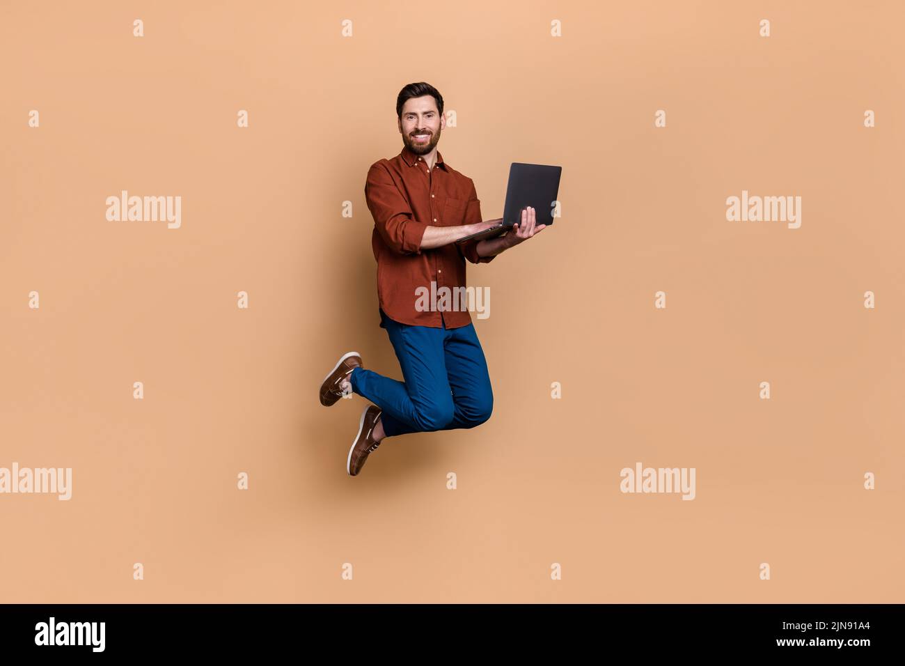 Full body photo of active cheerful guy jumping hold use wireless ...