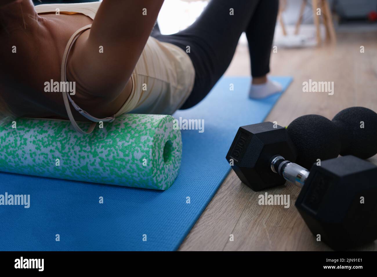 Closeup of woman riding cork massage roller to relieve tension in back ...