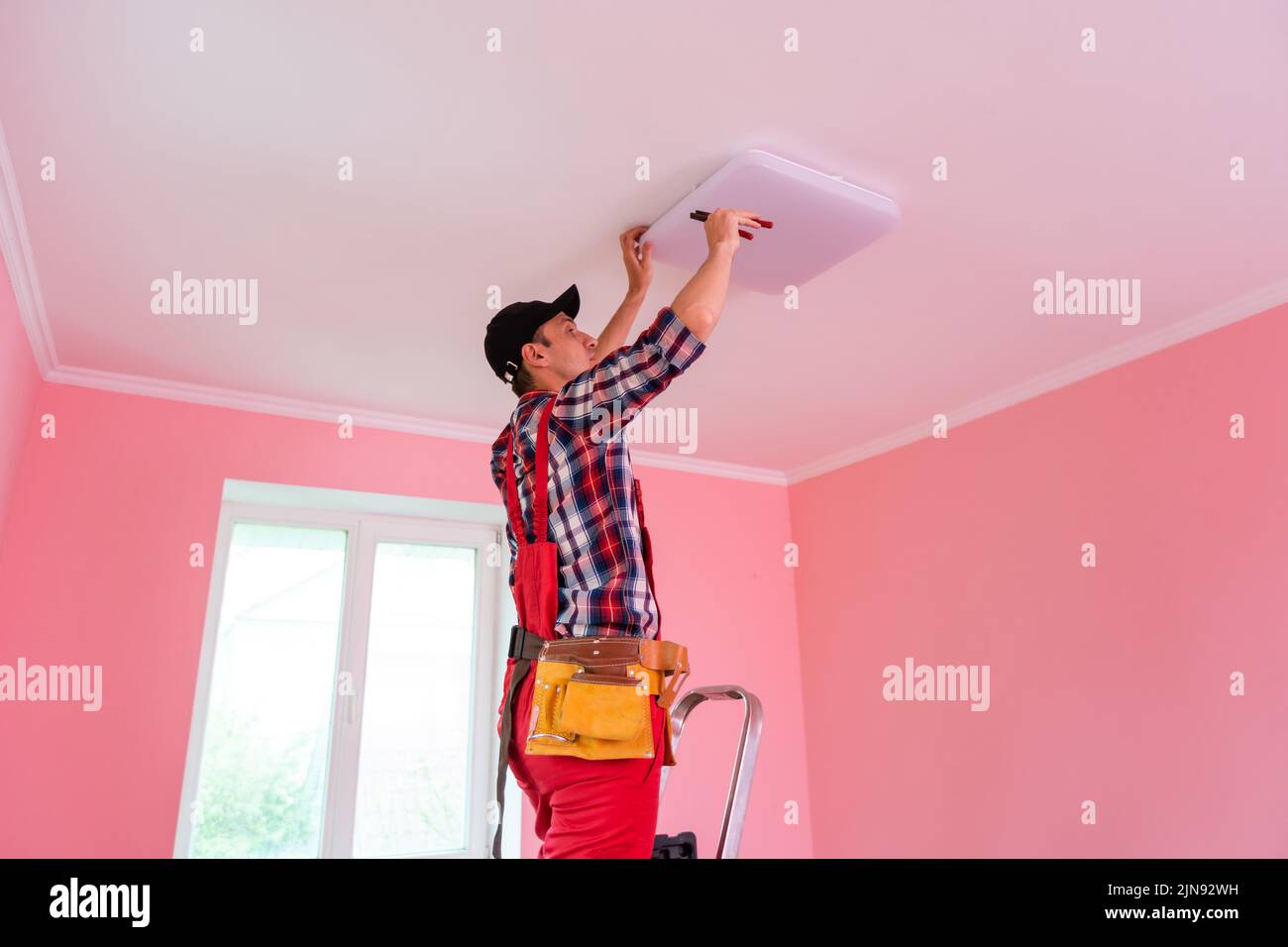 Electrician changing light bulb. Young man in overall work uniform ...
