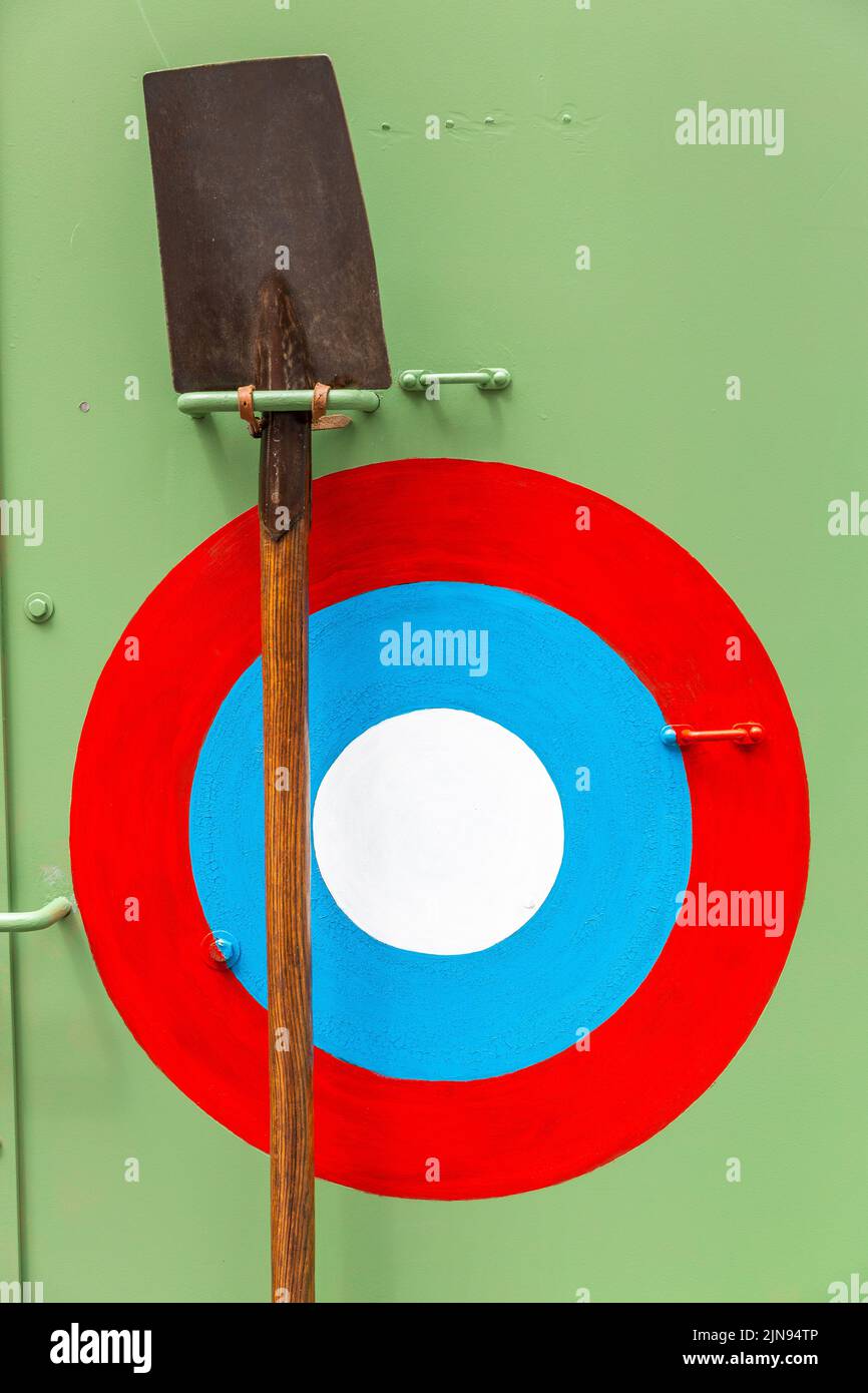 Spade attached to the side of an old military vehicle, next to a red ...