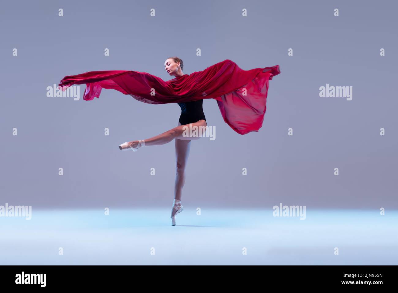 Portrait of young ballerina dancing with deep red clored fabric ...