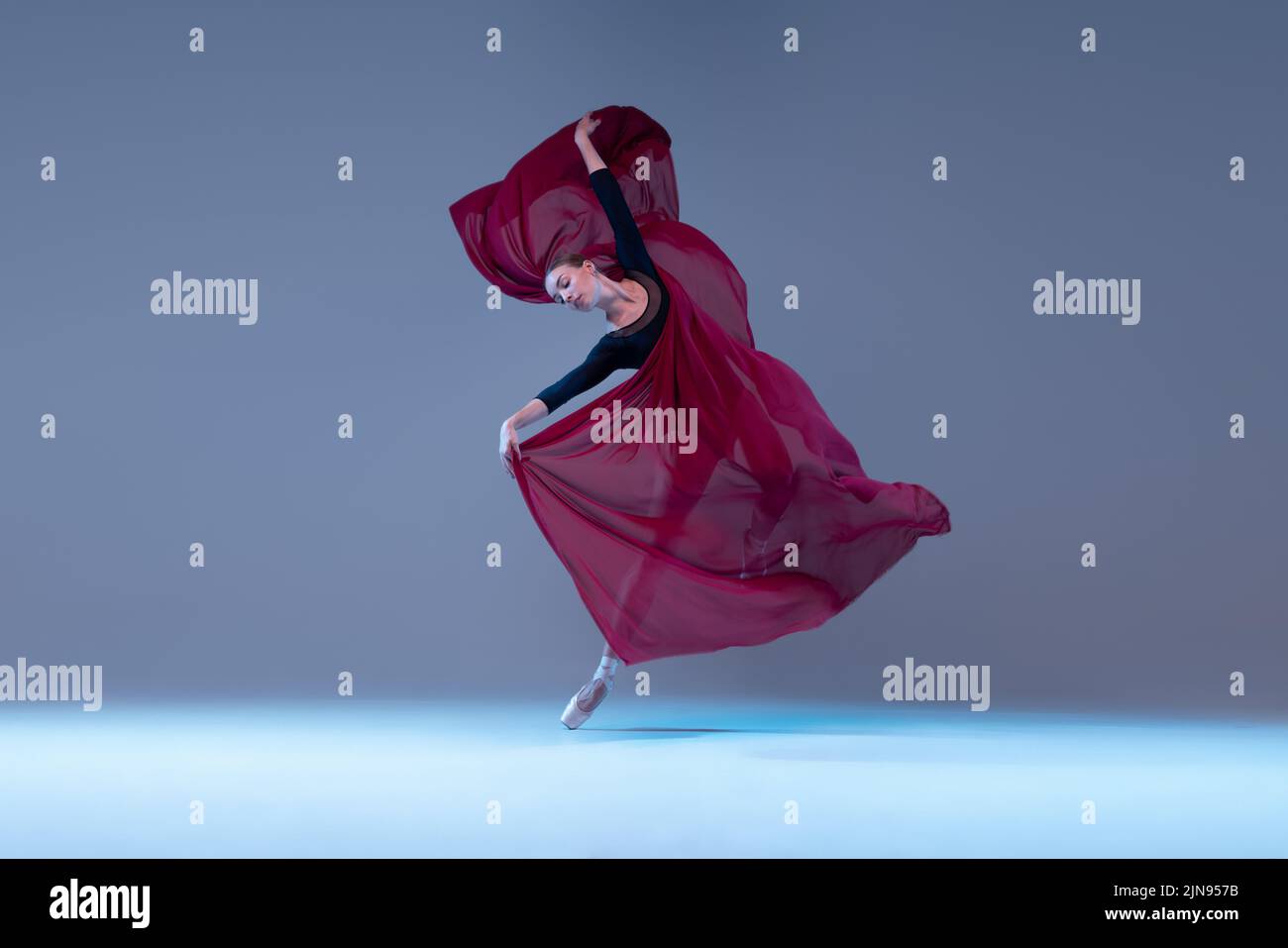 Portrait of young flexible ballerina dancing with transparent fabric ...