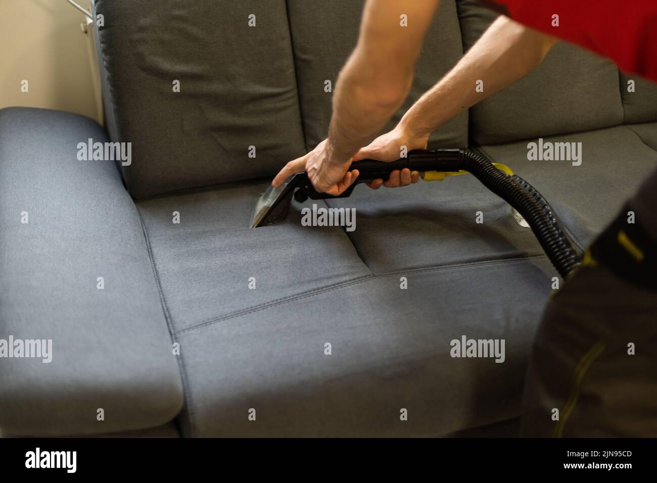 Man dry cleaner's employee cleaning sofa with professionally extraction ...