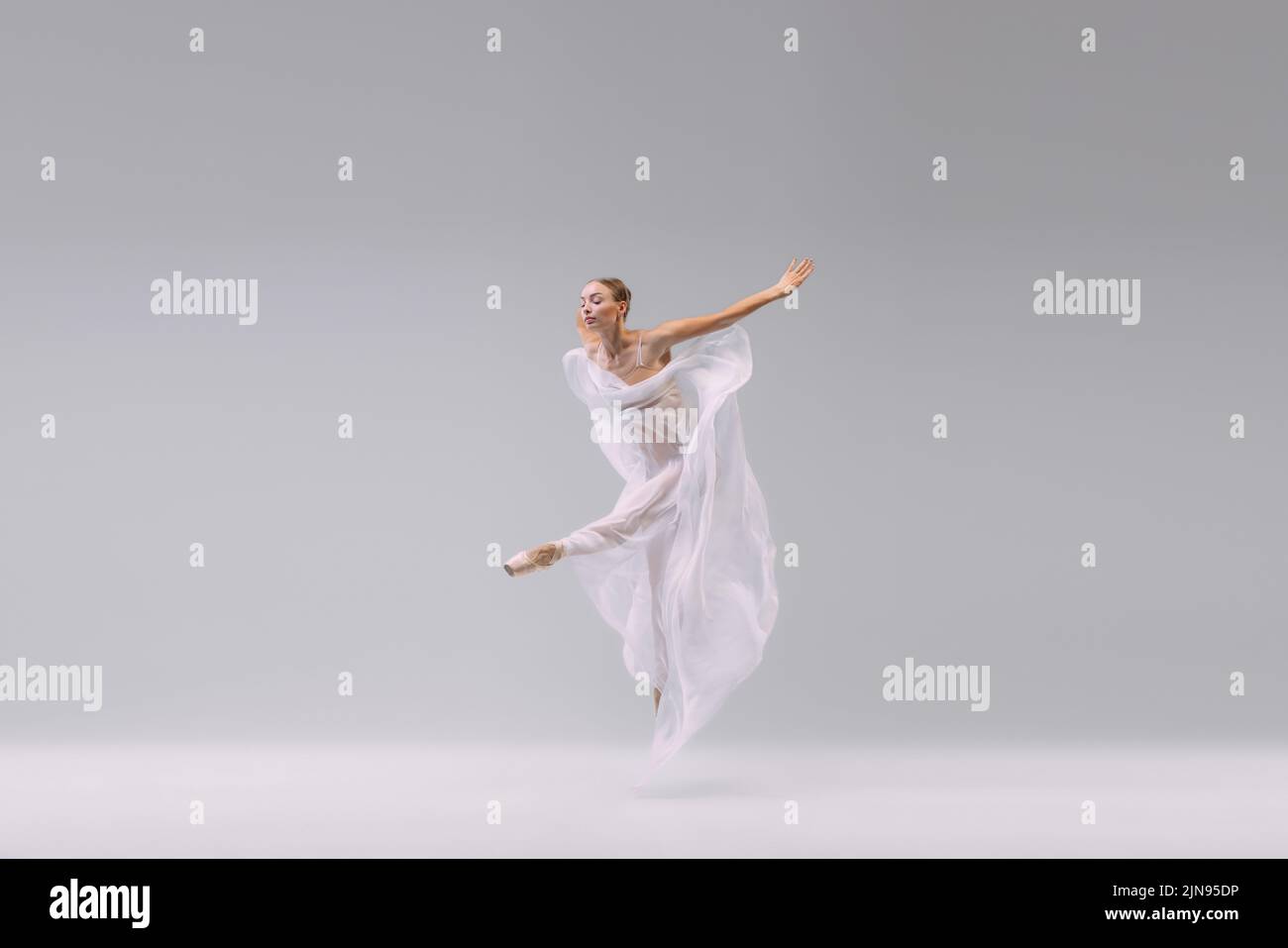 Portrait of young artistic ballerina dancing with transparent fabric ...