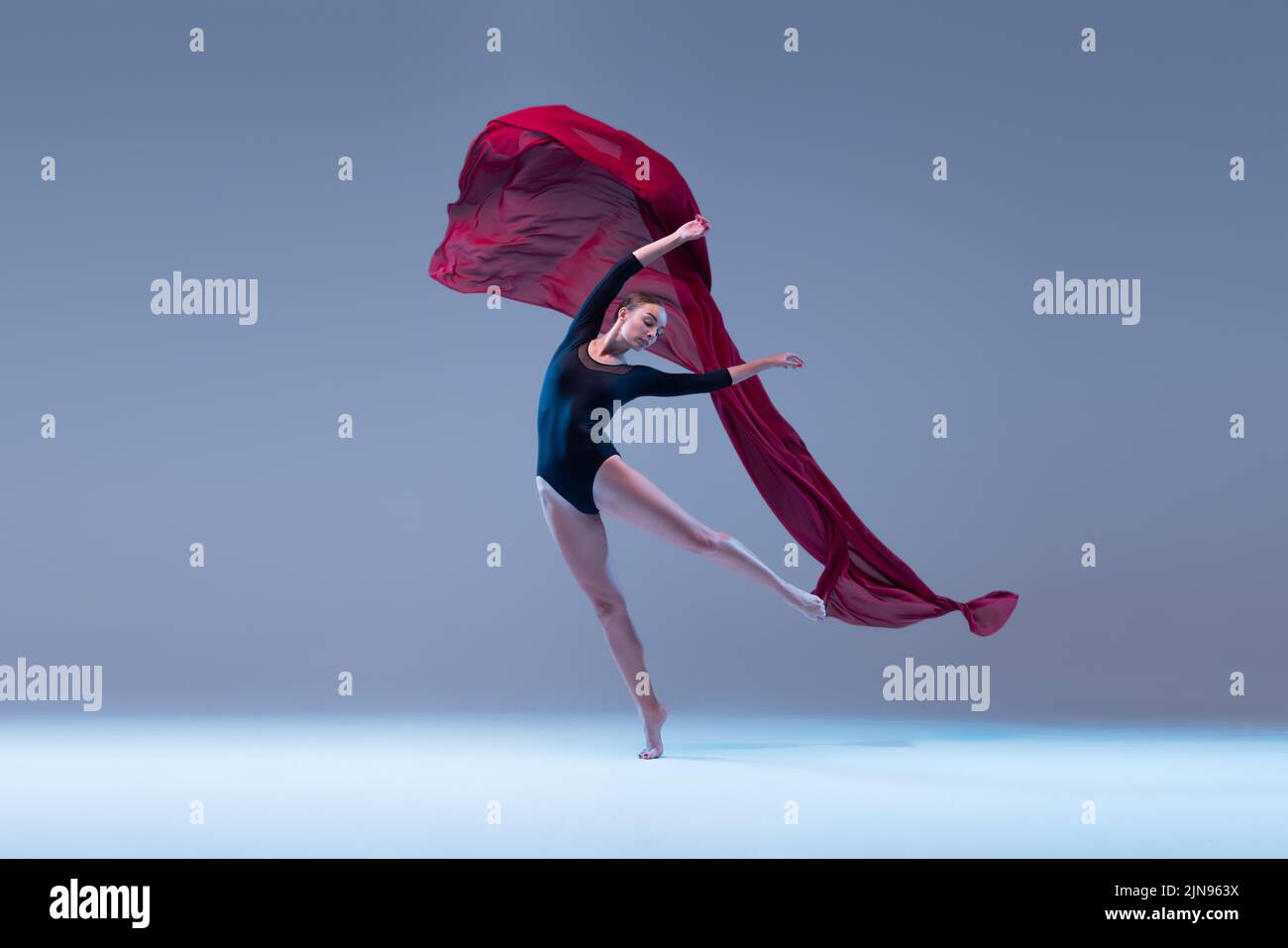 Portrait of young ballerina dancing with deep red fabric isolated over ...