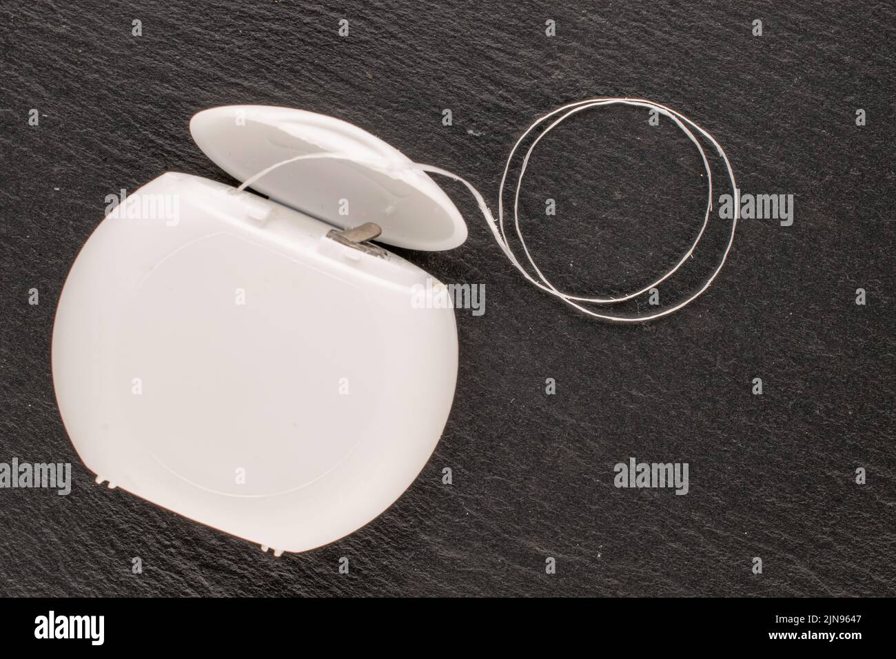 Dental hygienic floss in a plastic package on a slate stone, close-up ...
