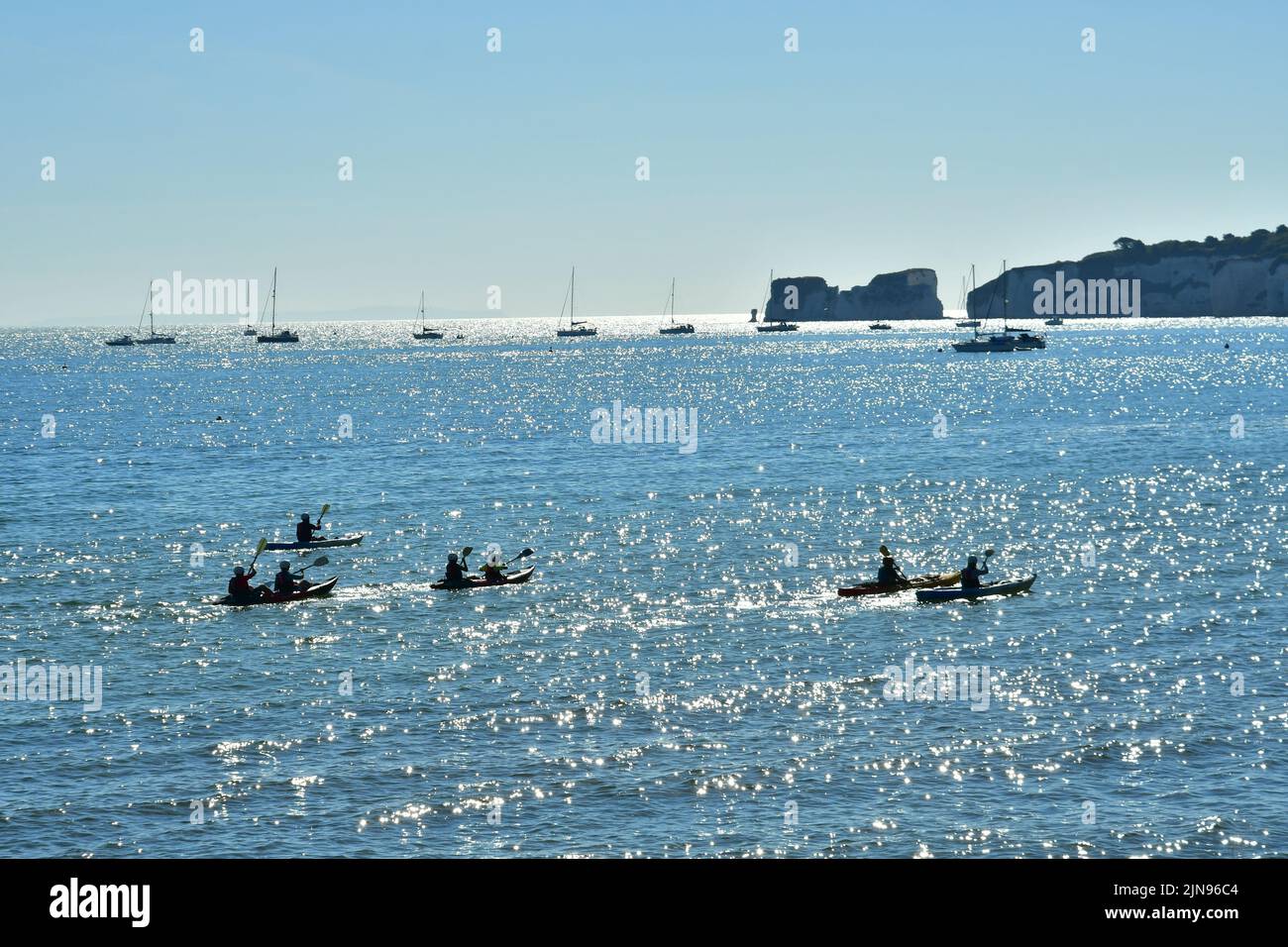 Kayakers on the sea at Shell Bay, Studland, Dorset in hot and sunny ...