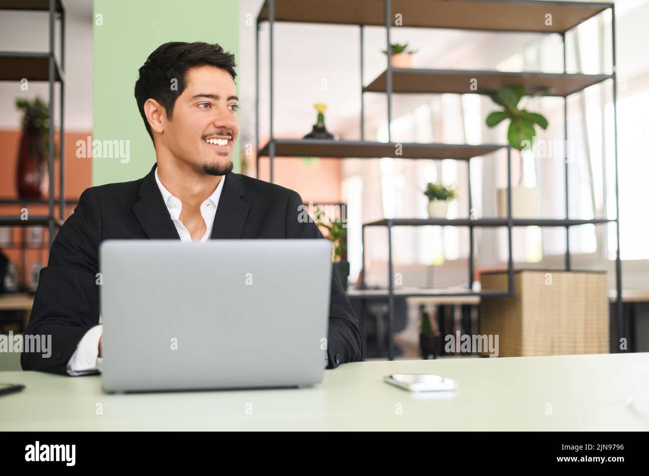 Confident young latin man work with laptop at the modern office ...