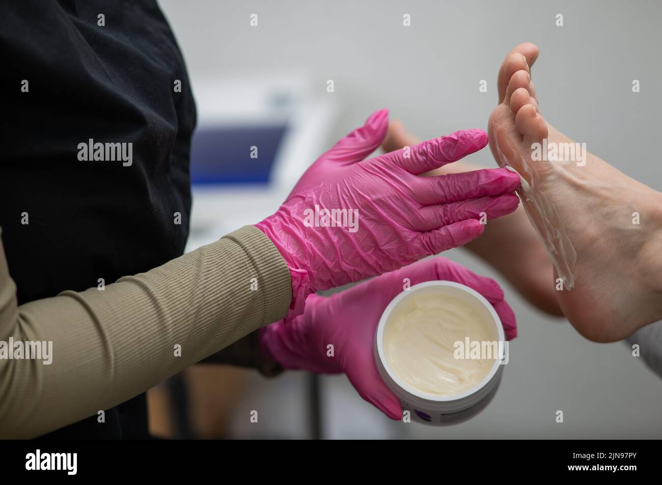 The master applies the cream and massages the feet of a female client ...