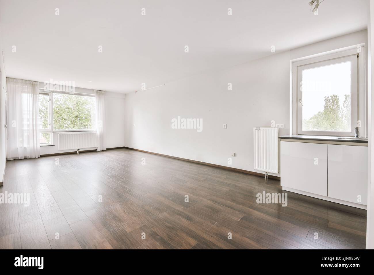 Interior of empty white kitchen with windows and wooden parquet floor ...