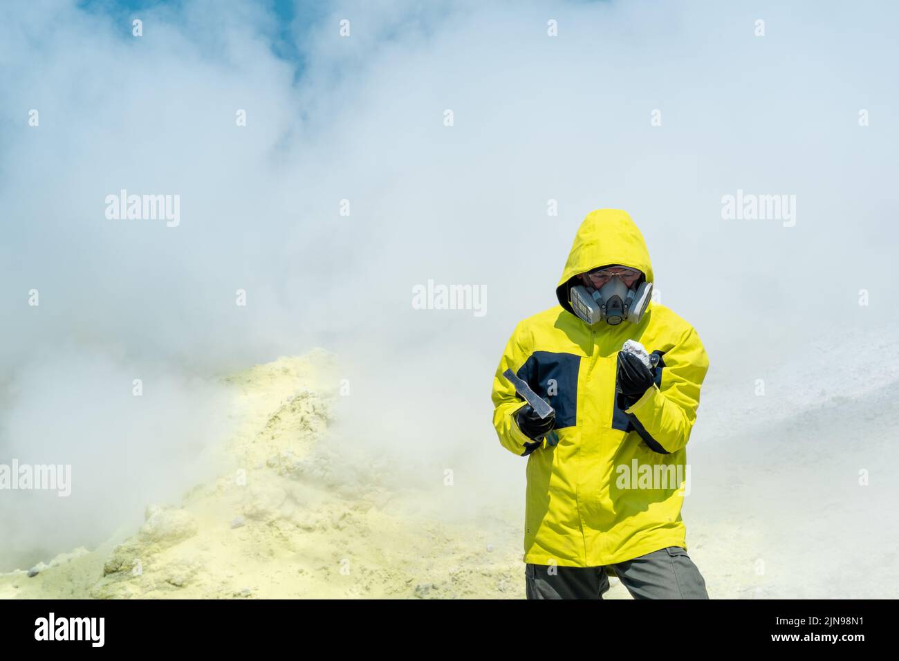 male volcano scientist on the slope of a volcano among the vapors of a ...