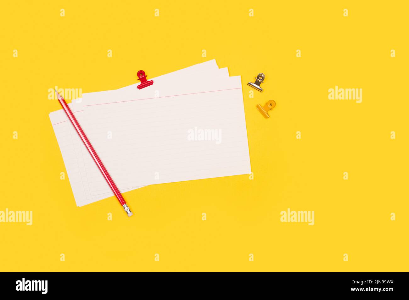Blank striped paper notes with a red pencil on a yellow background with ...