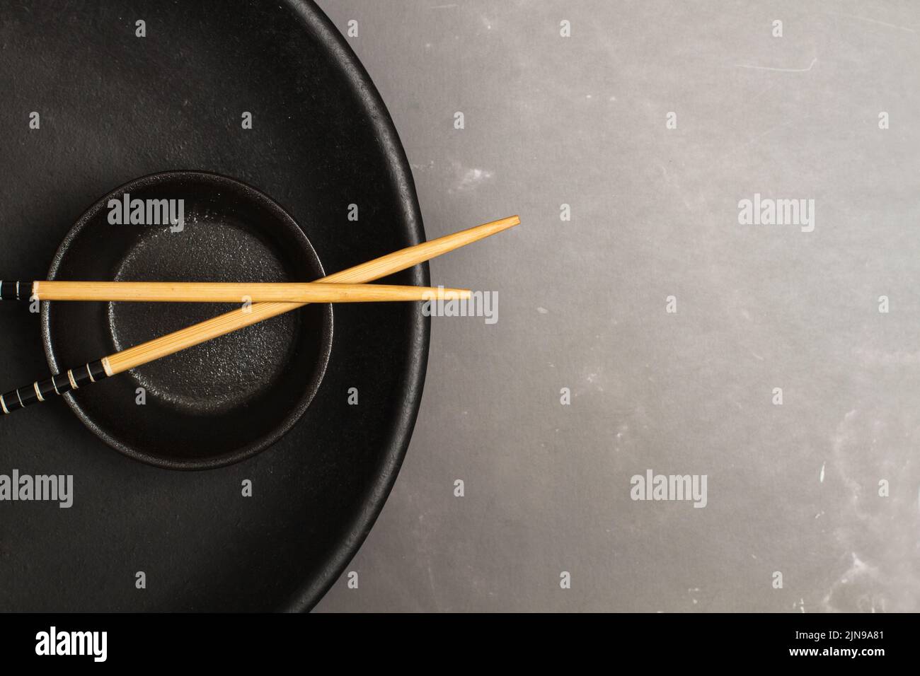 Black round dish, black bowl and chopsticks on a gray marble kitchen ...