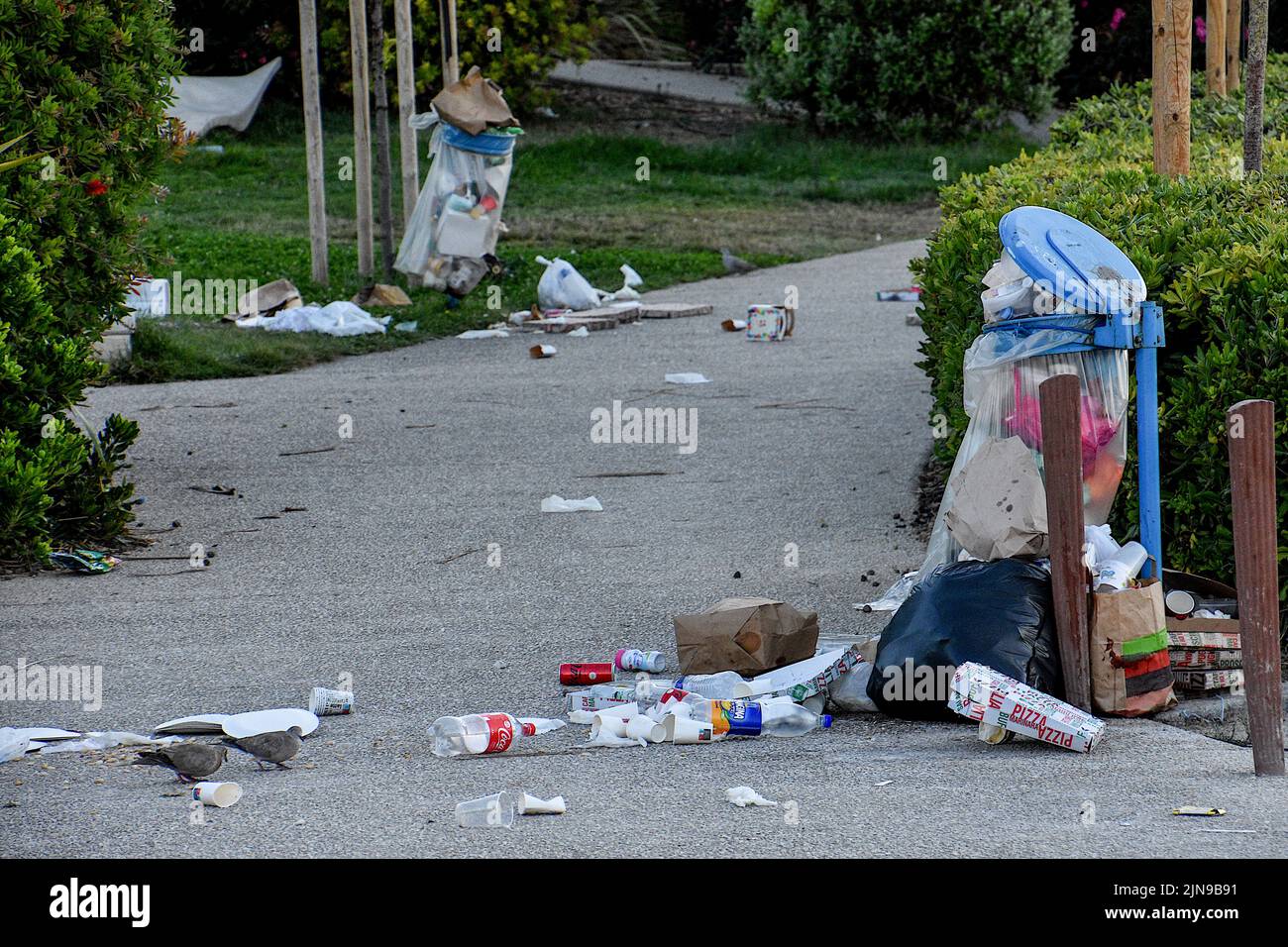 Garbage is strewn on the ground next to a full trashcan at Mistral Park ...