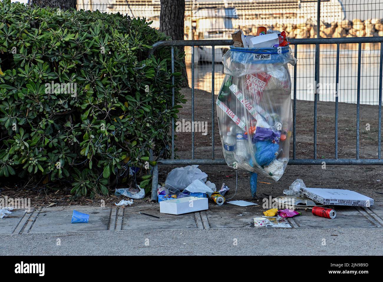 Garbage is strewn on the ground next to a full trashcan at Mistral Park ...