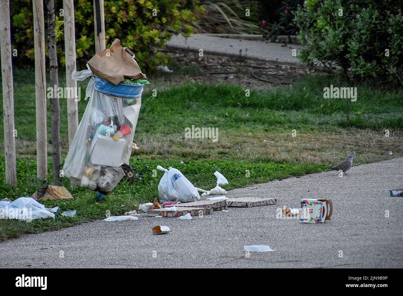 Garbage is strewn on the ground next to a full trashcan at Mistral Park ...