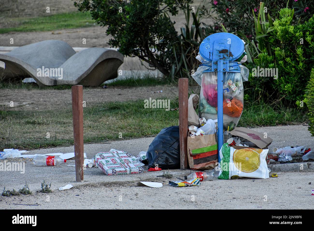 Garbage is strewn on the ground next to a full trashcan at Mistral Park ...