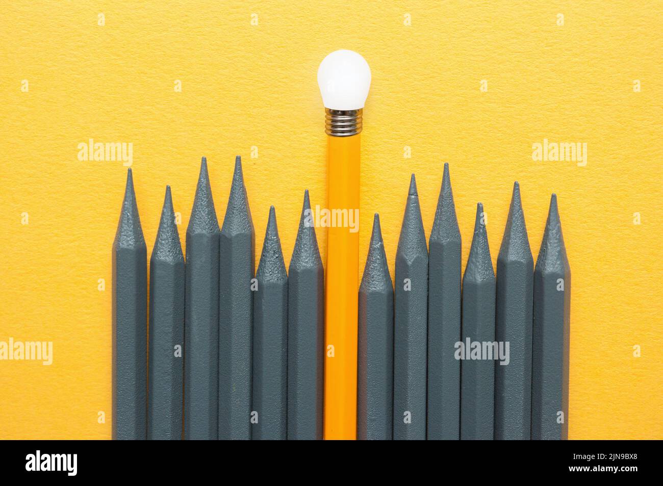 Orange pencil standing out amongst grey pencils with light bulb tip ...