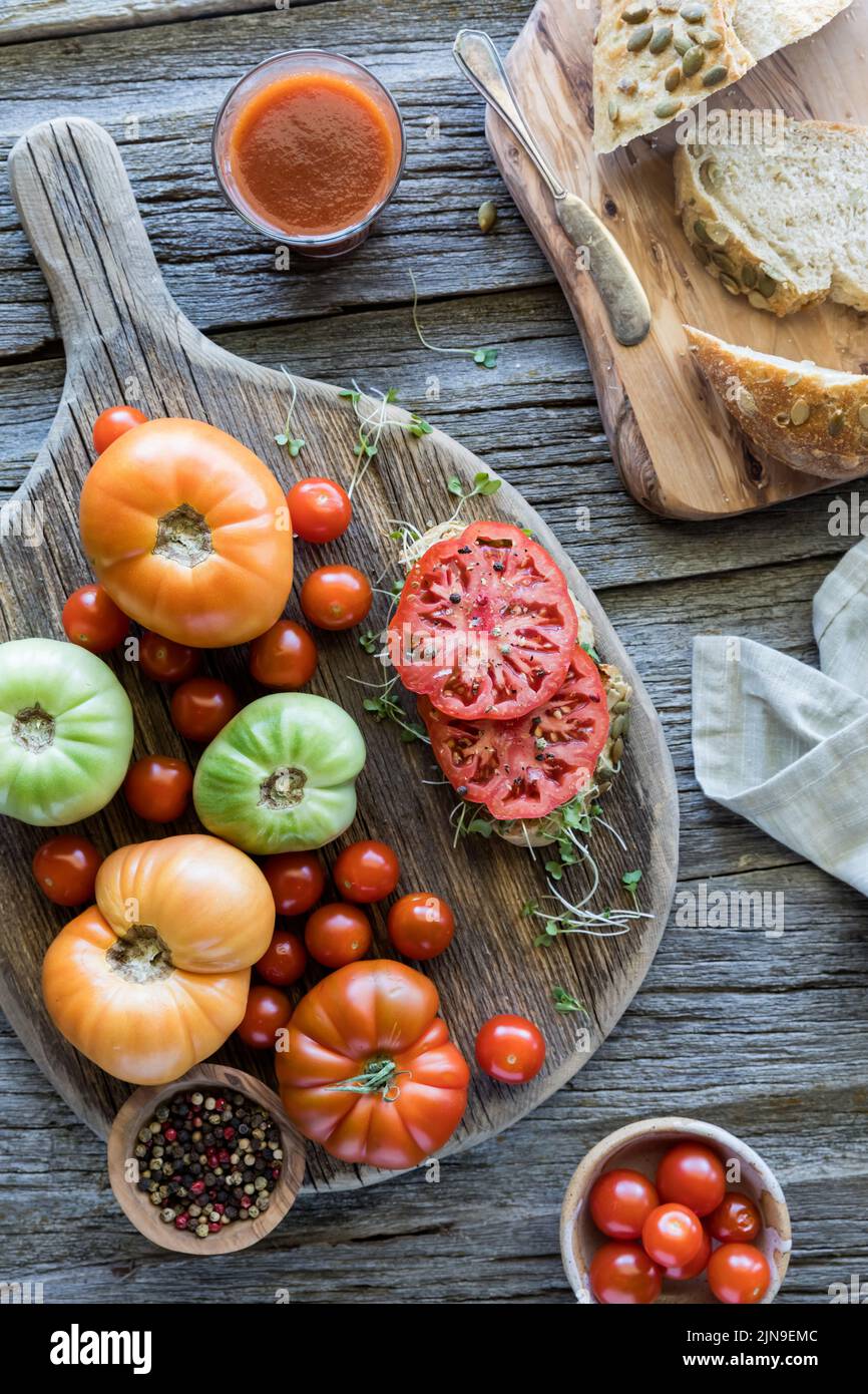 Several tomatoes on a rustic board with an open tomato sandwich Stock ...