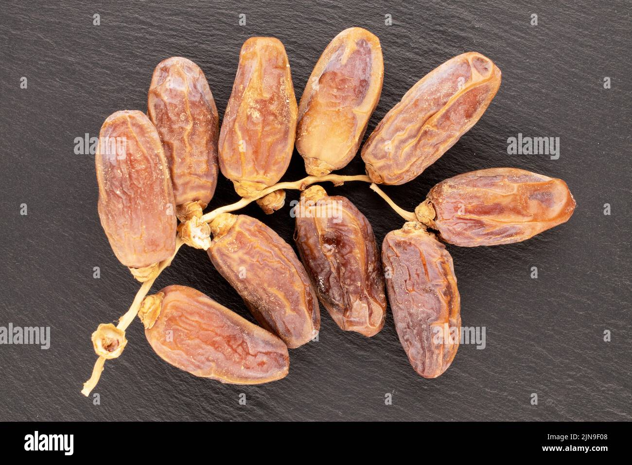 One branch with dry sweet dates on a slate stone, close-up, top view ...
