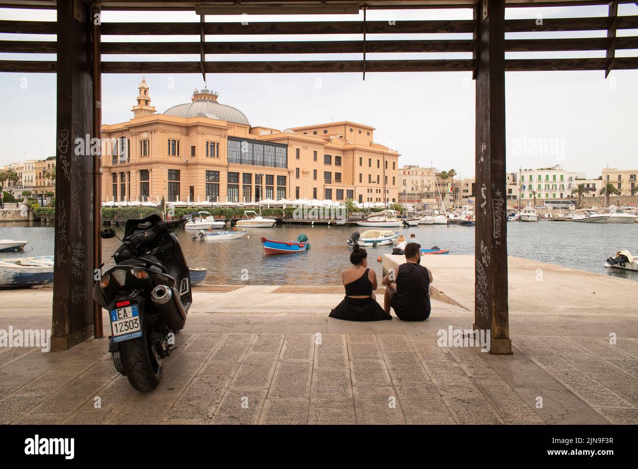 couple admiring Bari harbour from pier with parked motorbike Stock ...