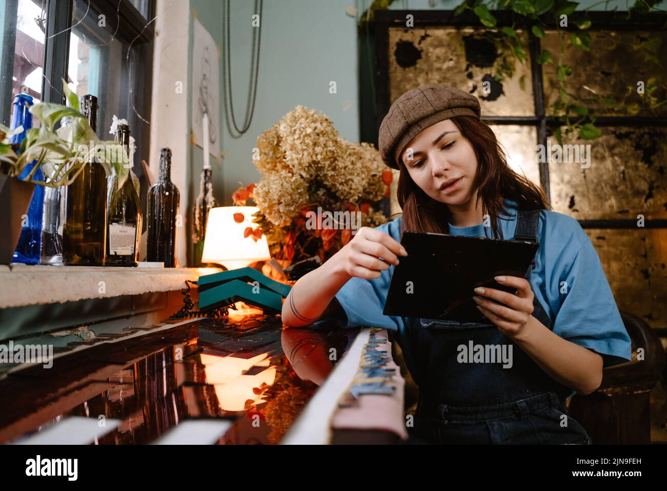 Young woman artist creating stain glass while working in her studio ...