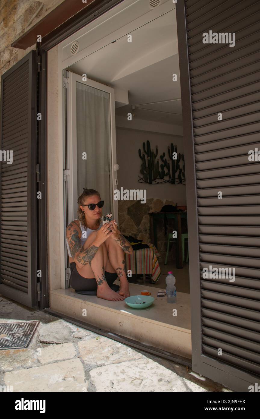 Young woman relaxing and checking her phone while having coffee and ...