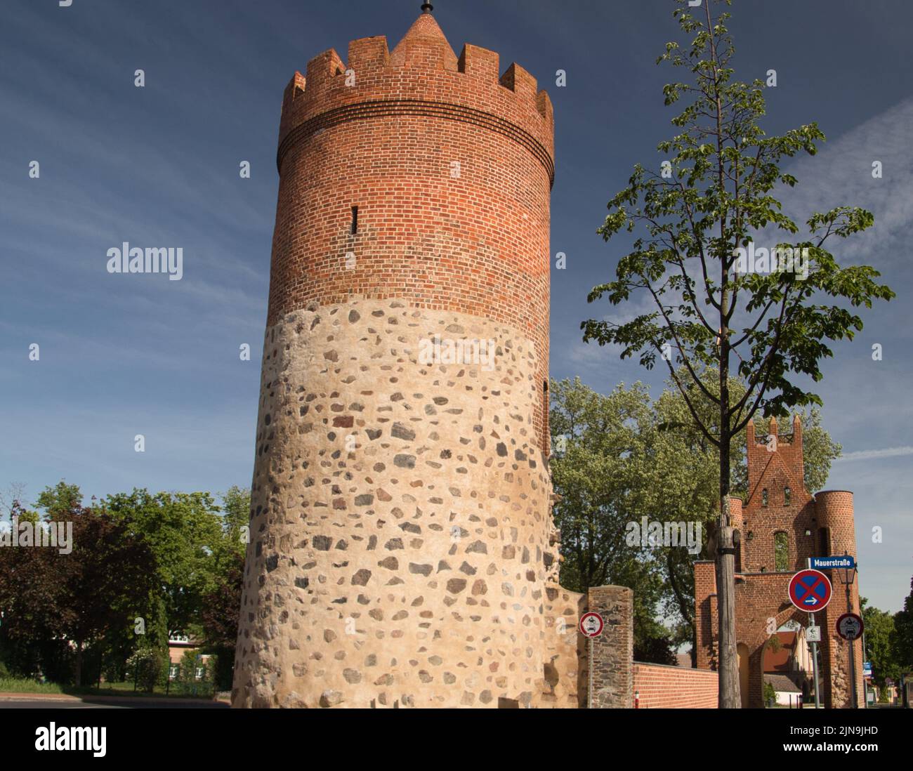 A round brick tower under blue cloudy sky with green trees Stock Photo ...