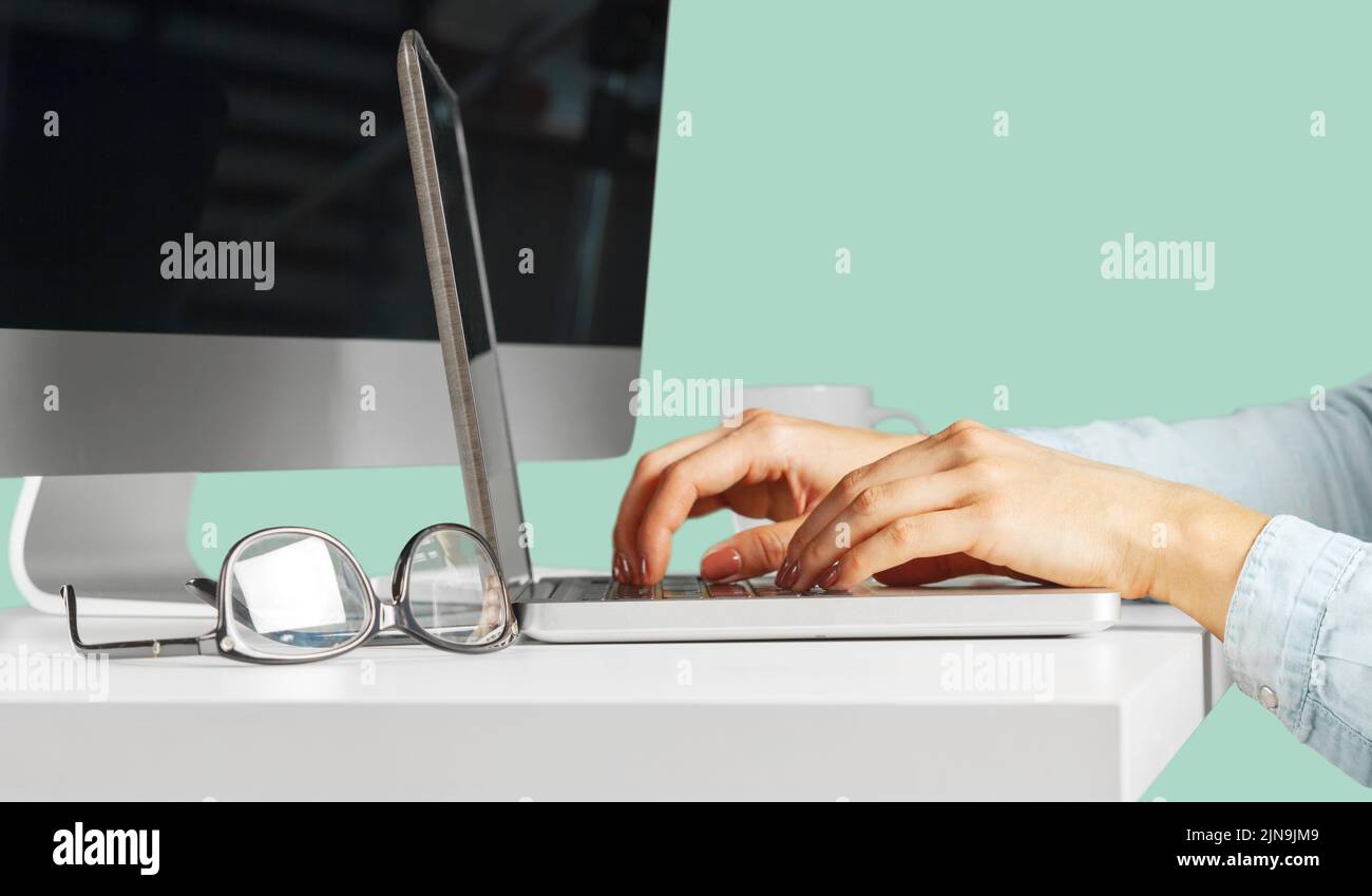 Young woman sitting at the table with open netbook computer. Female ...